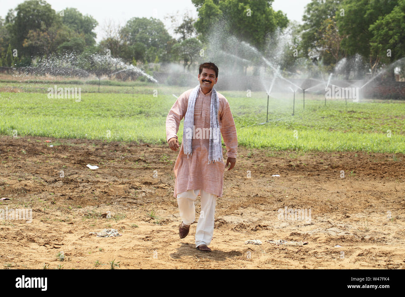 Farmer walking with sprinklers in the background Stock Photo - Alamy