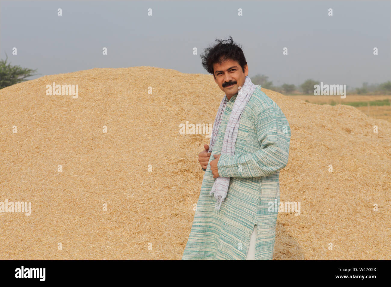 Farmer standing in front of pile of husk Stock Photo - Alamy