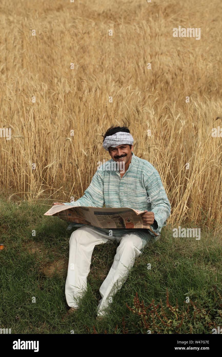 Indian farmer reading a newspaper in a field Stock Photo - Alamy