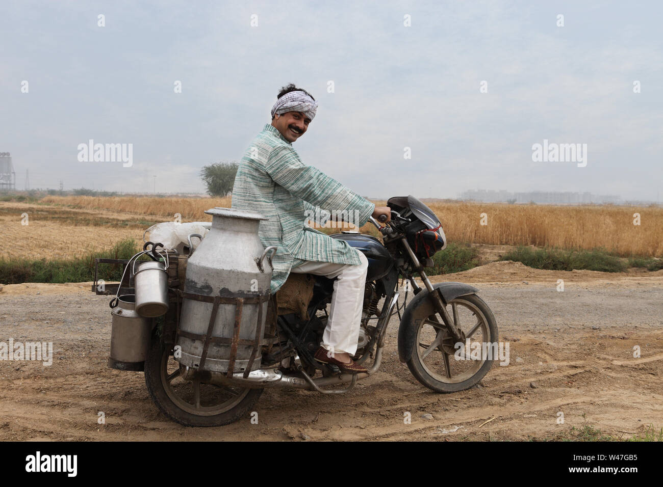 Indian milkman delivering milk on a motorcycle Stock Photo - Alamy