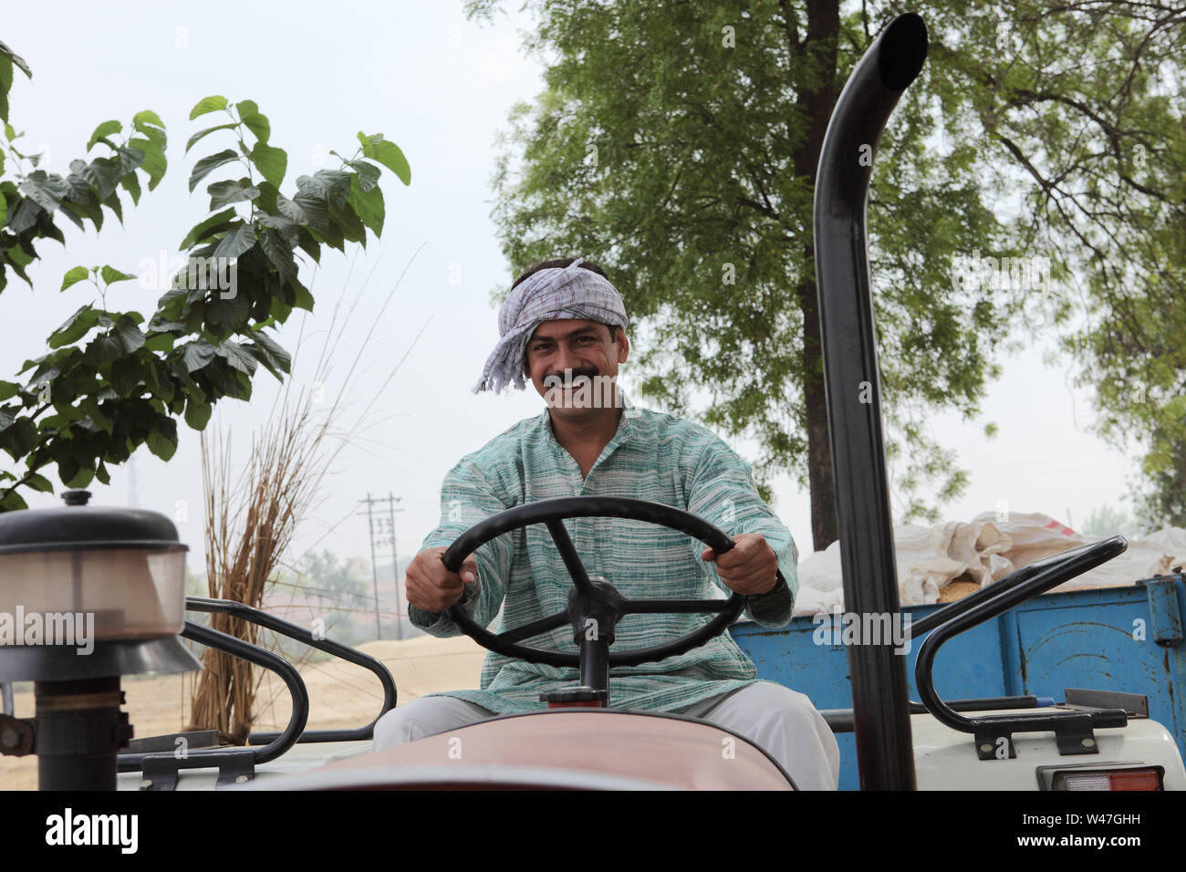 Farmer driving a tractor Stock Photo - Alamy