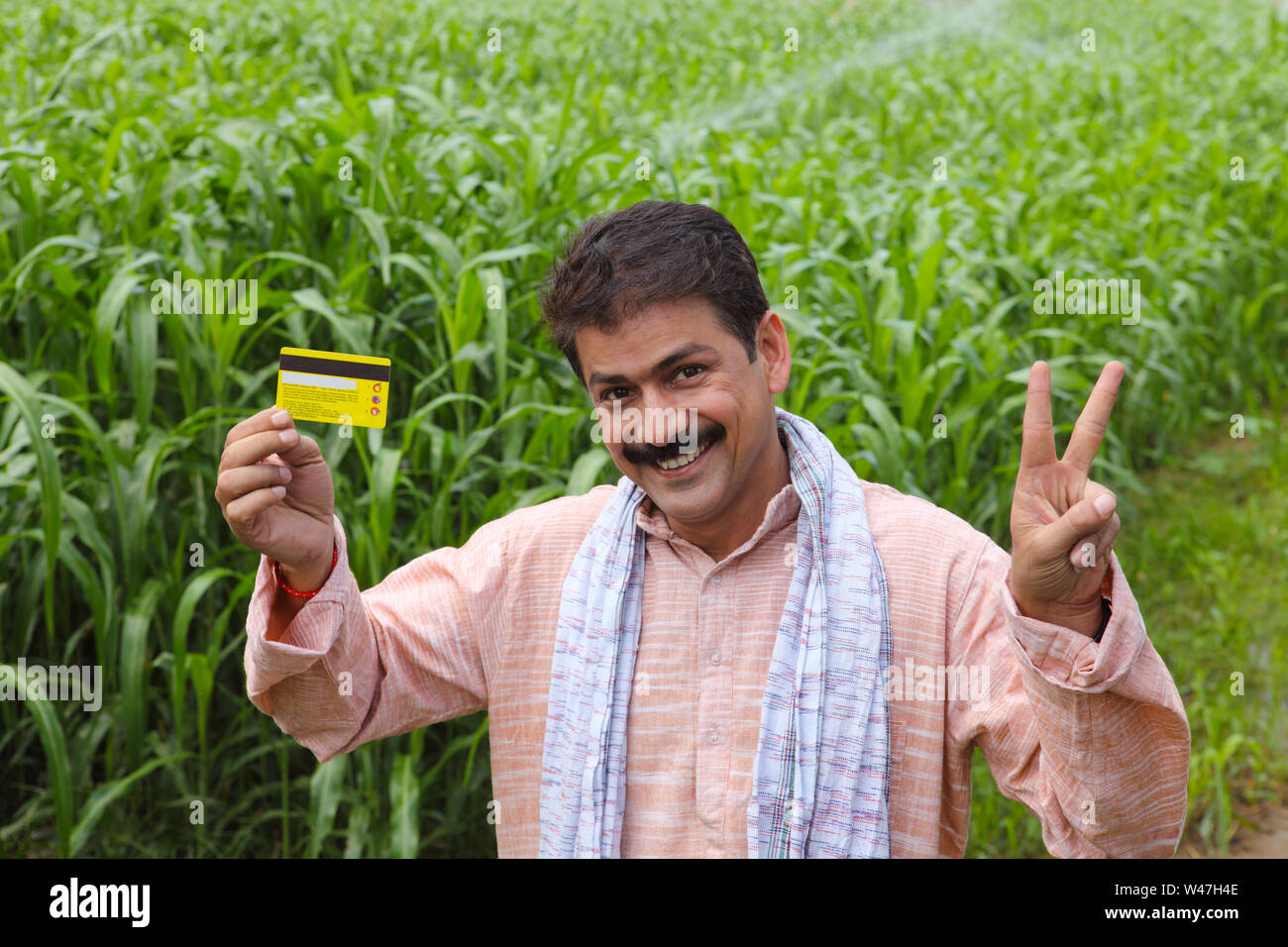 Farmer holding credit card and showing V sign Stock Photo - Alamy