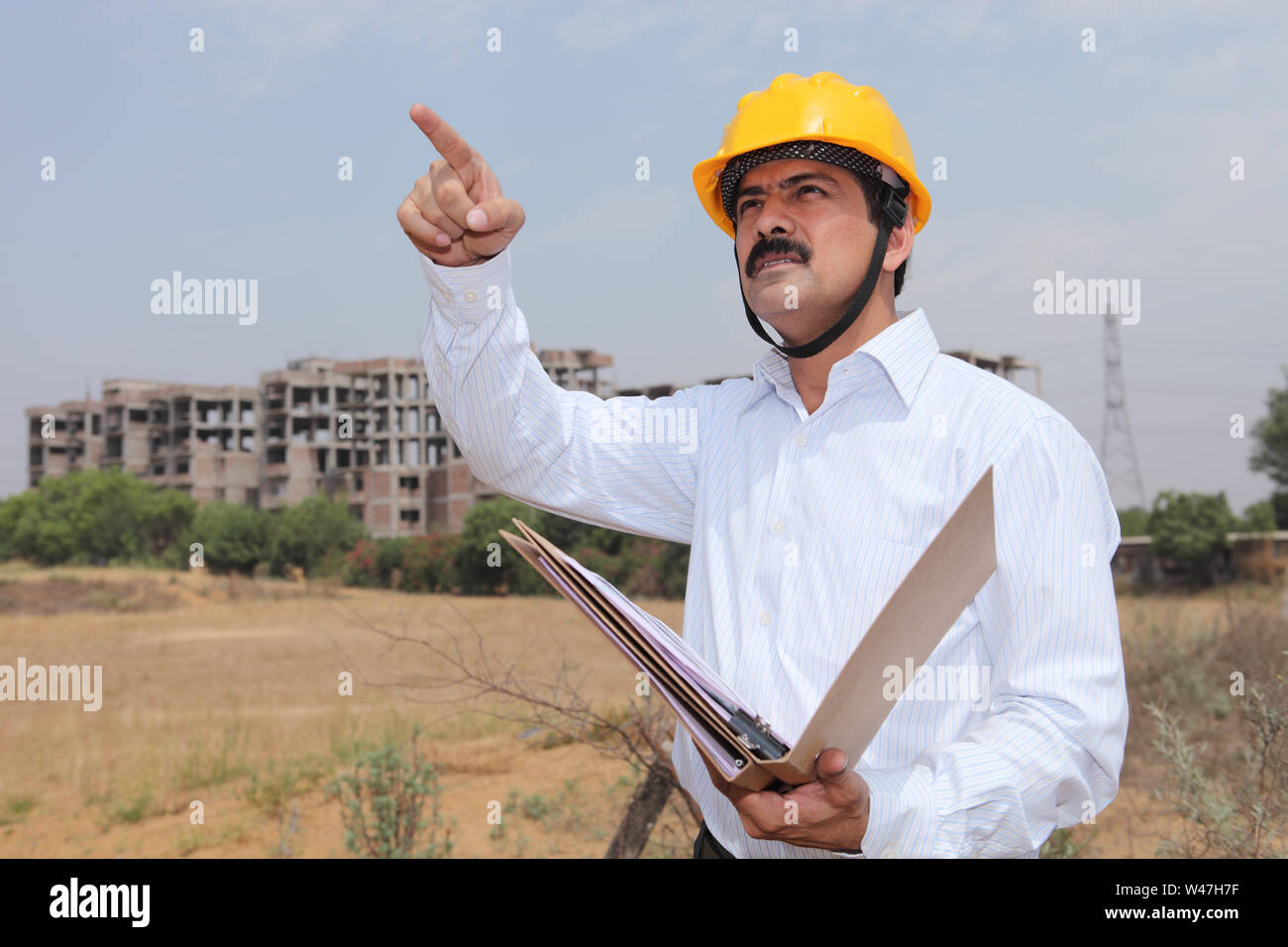 Architect pointing with construction site in the background Stock Photo ...