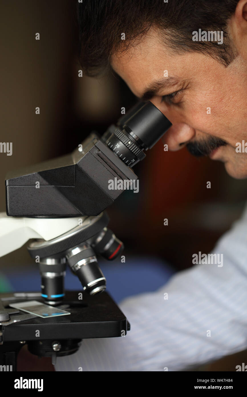Doctor examining through microscope Stock Photo - Alamy