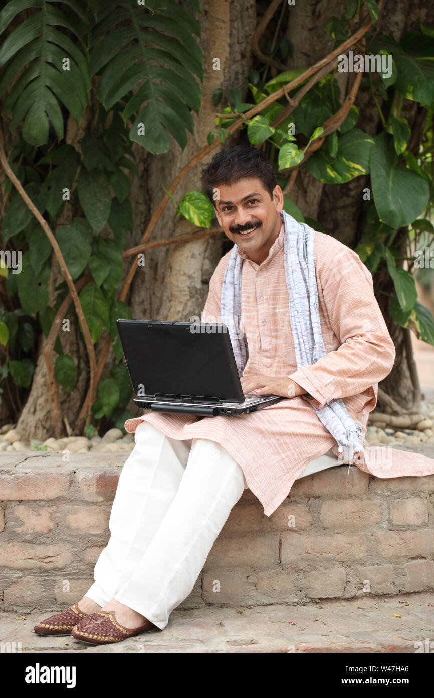 Rural man using a laptop under a tree Stock Photo - Alamy
