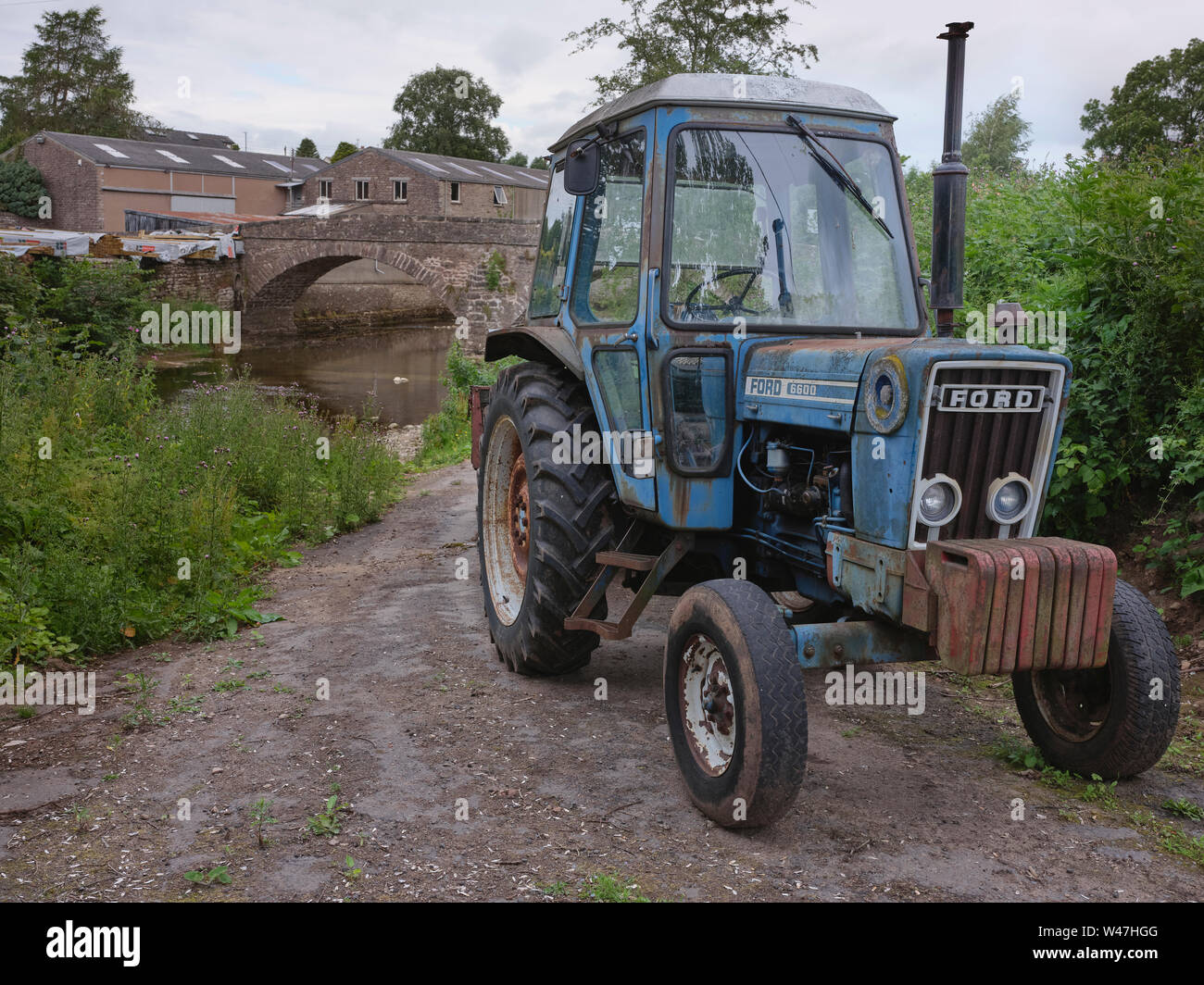 An old and rusting blue Ford 6600 tractor is parked by the River Eden ...