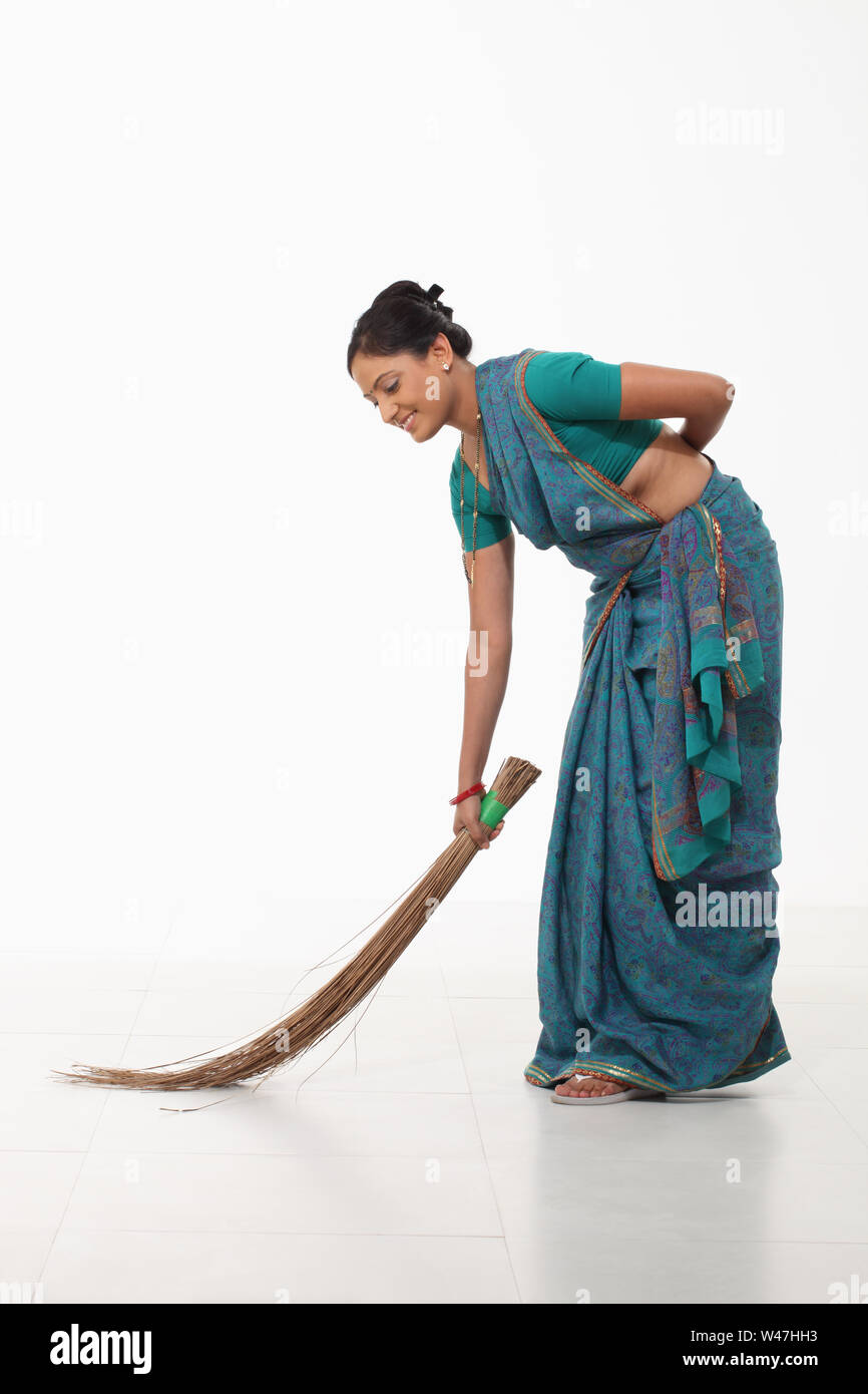 Woman sweeping floor and smiling Stock Photo - Alamy