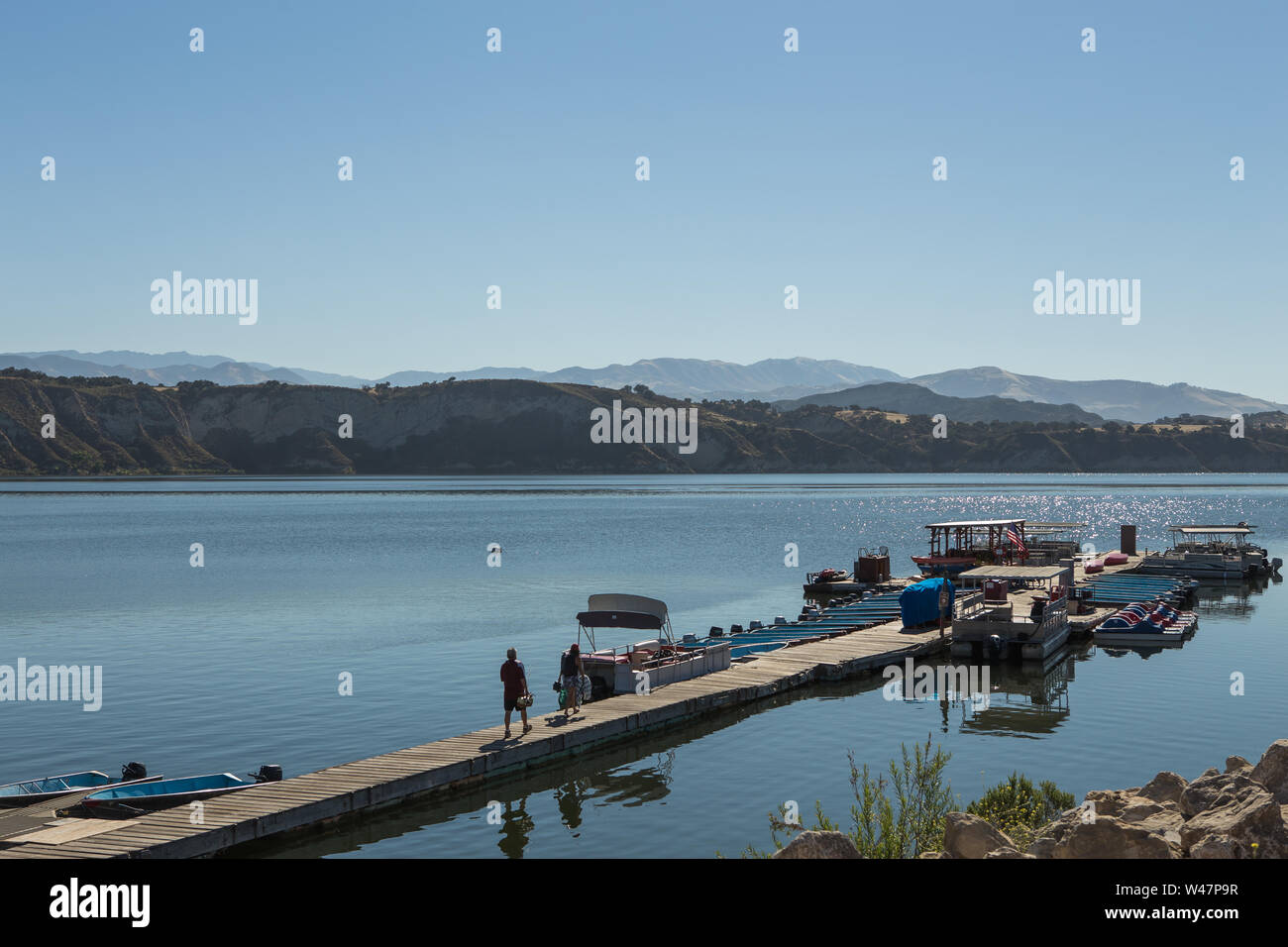 A couple walk out along the Wood boat dock / jetty at Lake Cachuma to ...