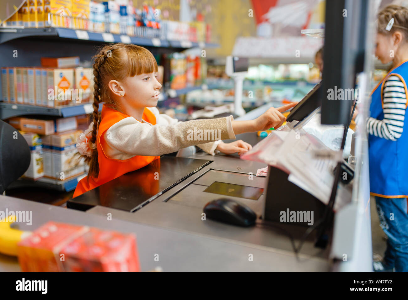 Cute girl in uniform at the cash register playing saleswoman, playroom ...