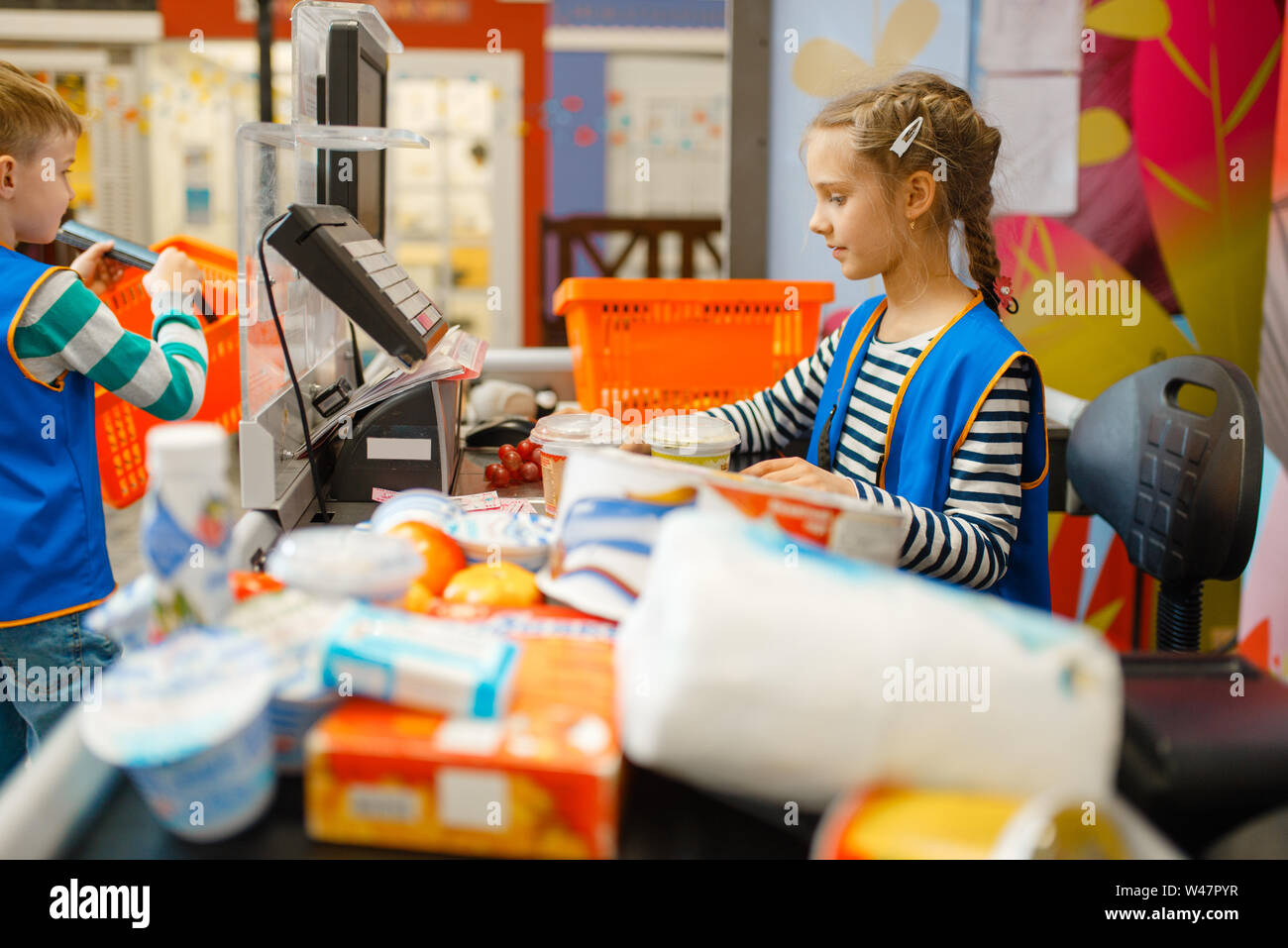 Cute girl in uniform at the cash register playing saleswoman, playroom ...