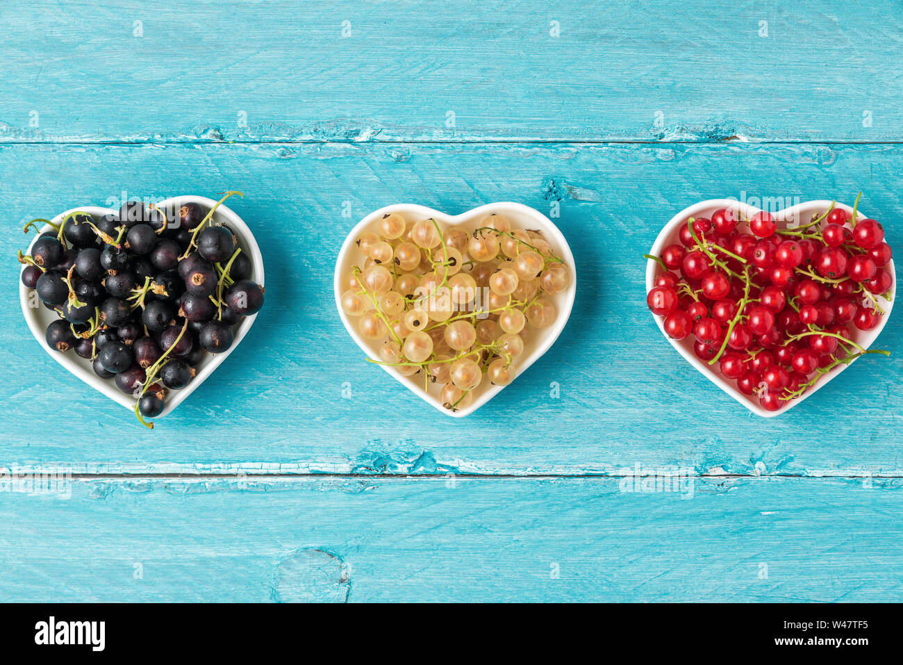 variety of currant berries black, red and white in heart shape bowls on ...
