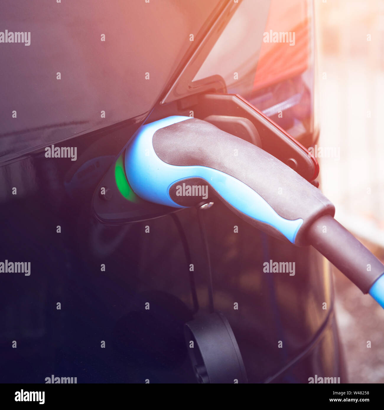 Charging modern electric car on the street car parking, sun flare ...