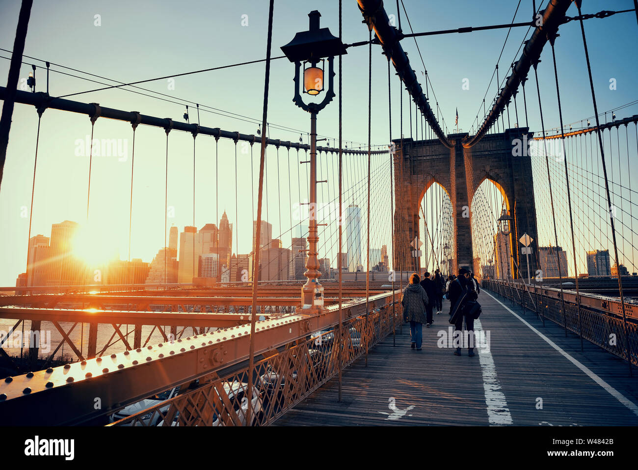 Walk on Brooklyn Bridge with pedestrians at sunset in downtown ...
