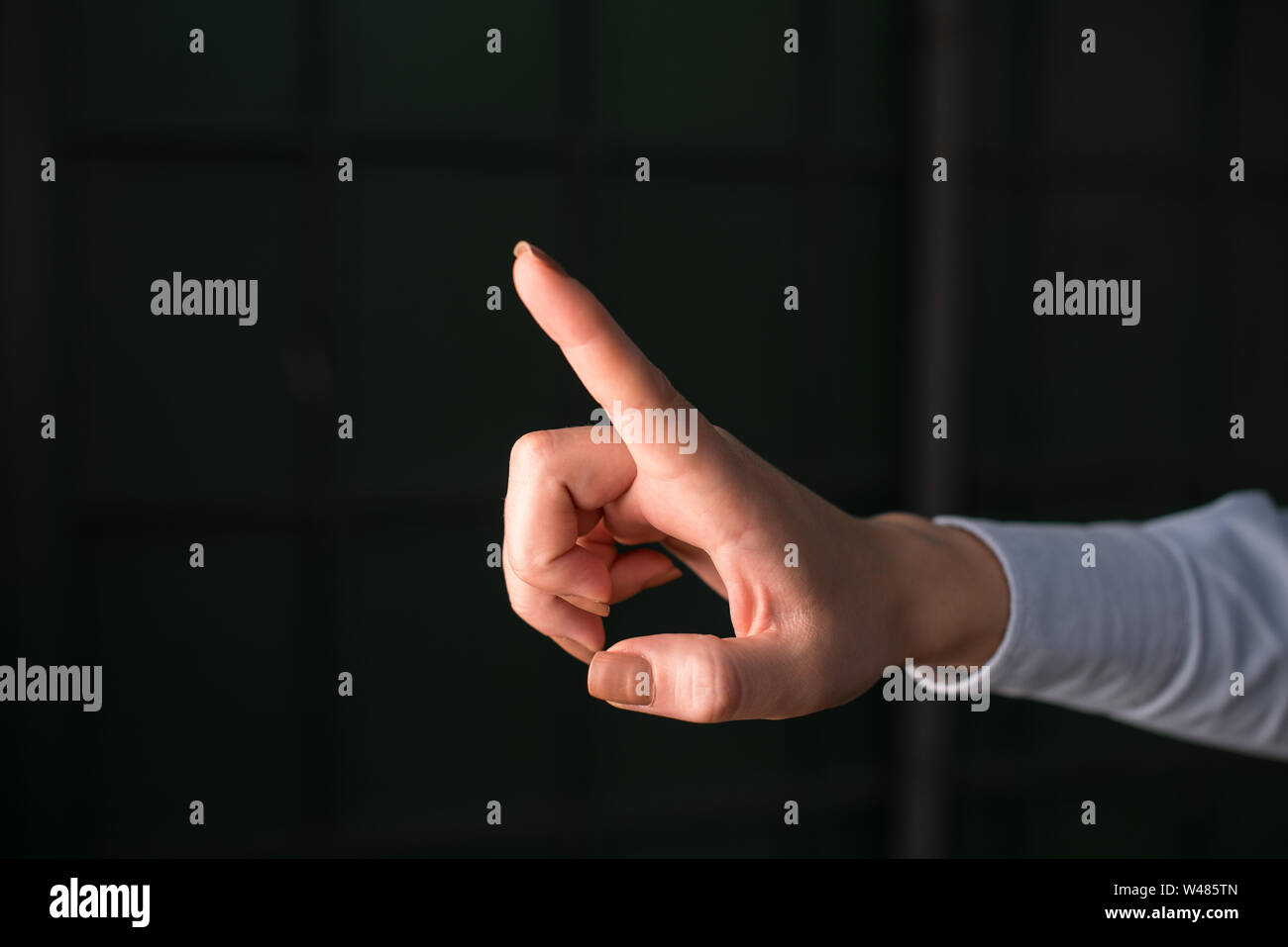 Finger pointing in the empty space. Dark background with hand pointing ...