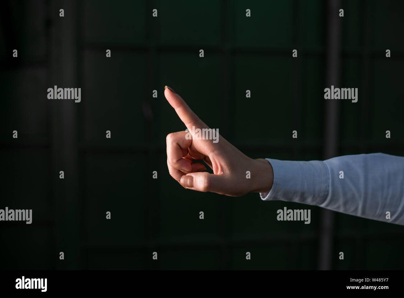 Finger pointing in the empty space. Dark background with hand pointing ...