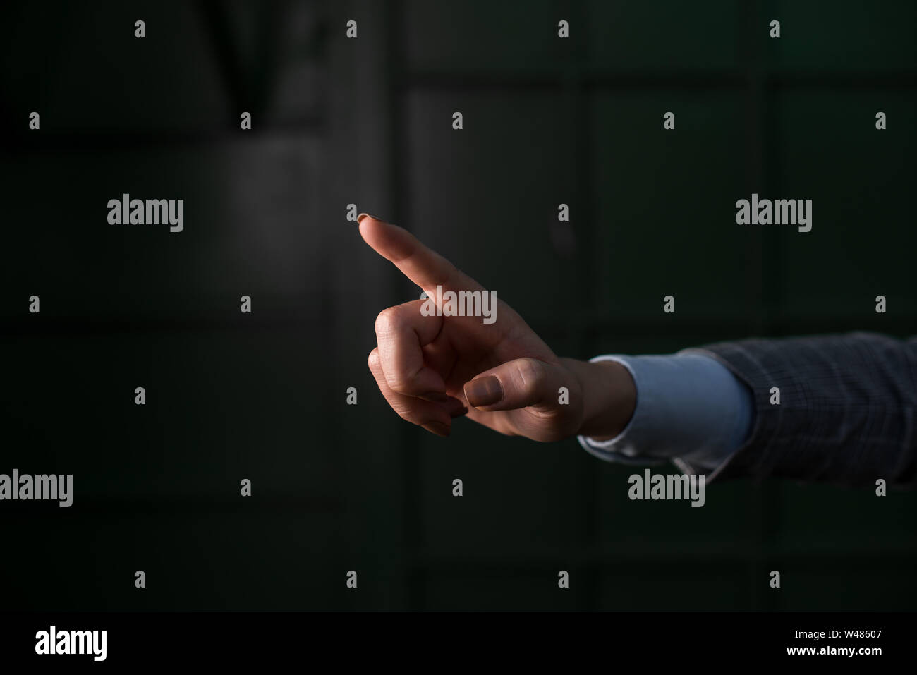 Finger pointing in the empty space. Dark background with hand pointing ...