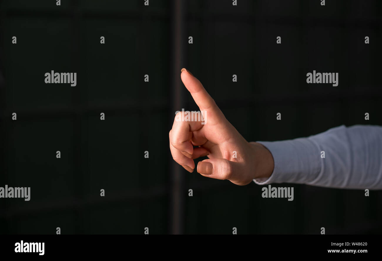 Finger pointing in the empty space. Dark background with hand pointing ...