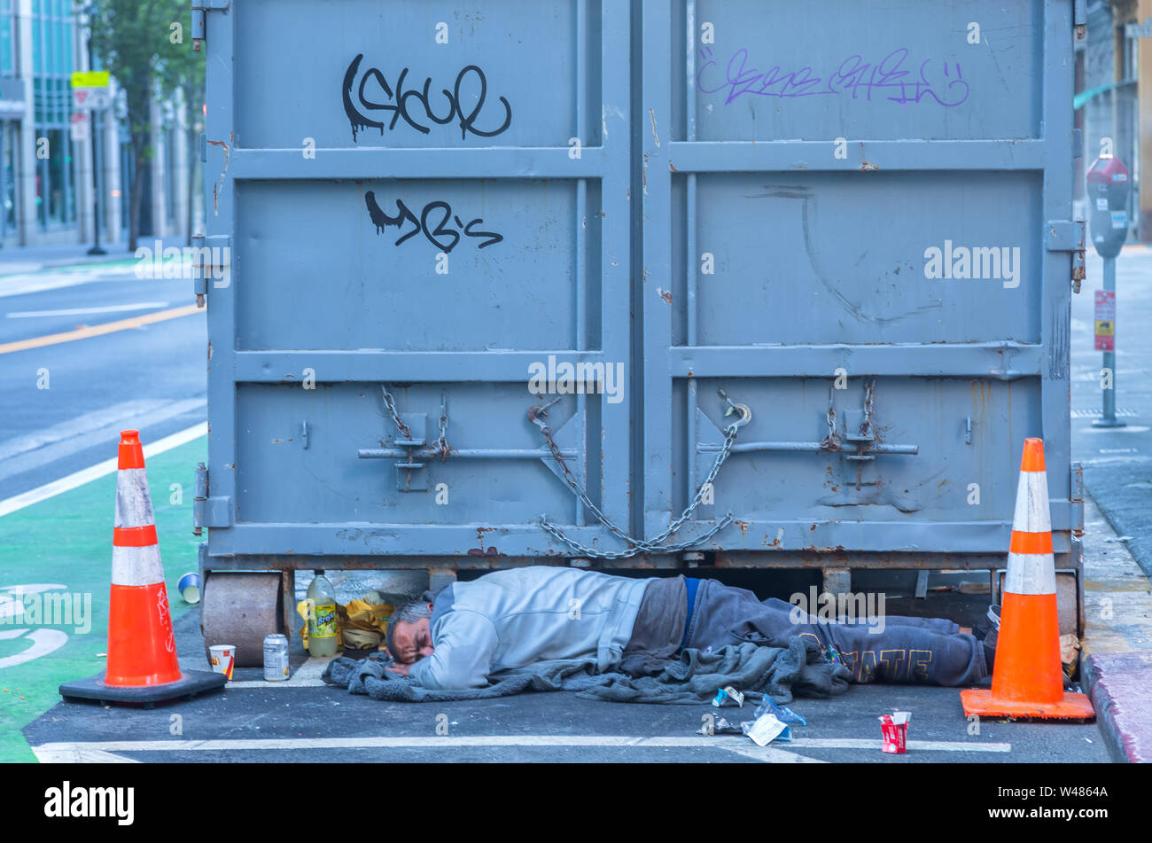 A homeless man sleep by the garbage container on the street of San ...