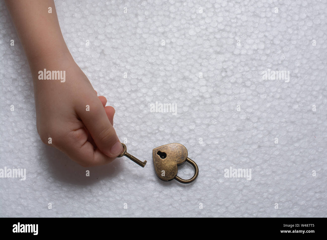 Hand holding a heart shaped lock and key on a white background Stock ...