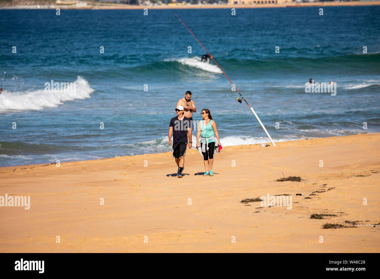 Man and woman exercise on narrabeen beach in Sydney on a sunny winters ...