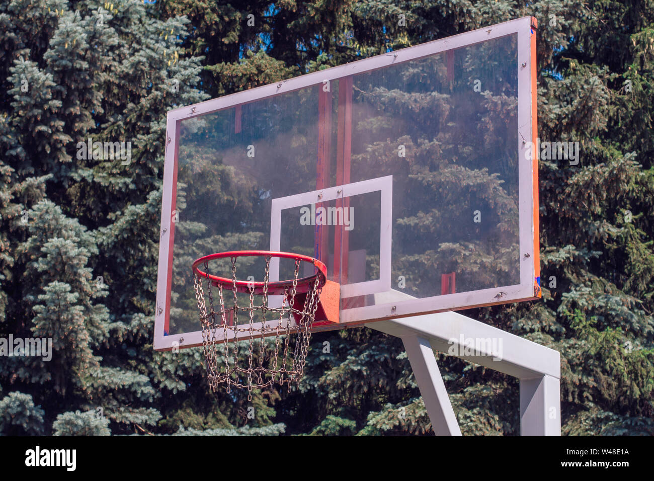 Outdoor basketball ring in front of green trees background. Sport ...