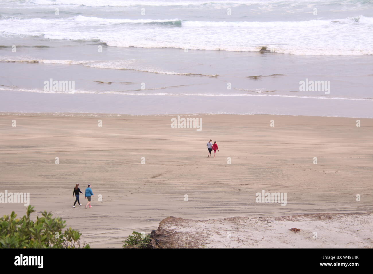 People Walking along the beach shoreline Stock Photo - Alamy