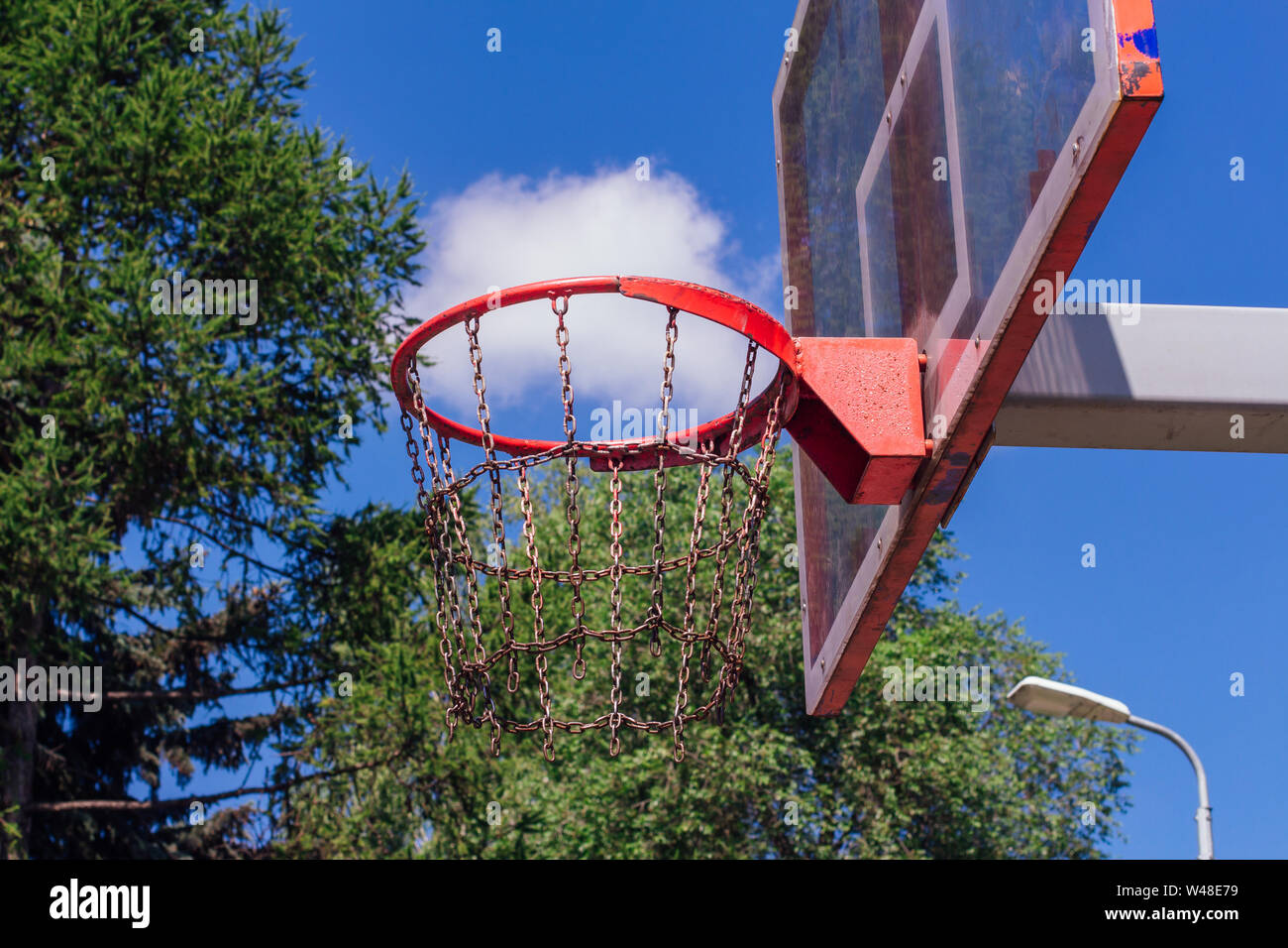 Outdoor basketball ring in front of green trees background. Sport ...