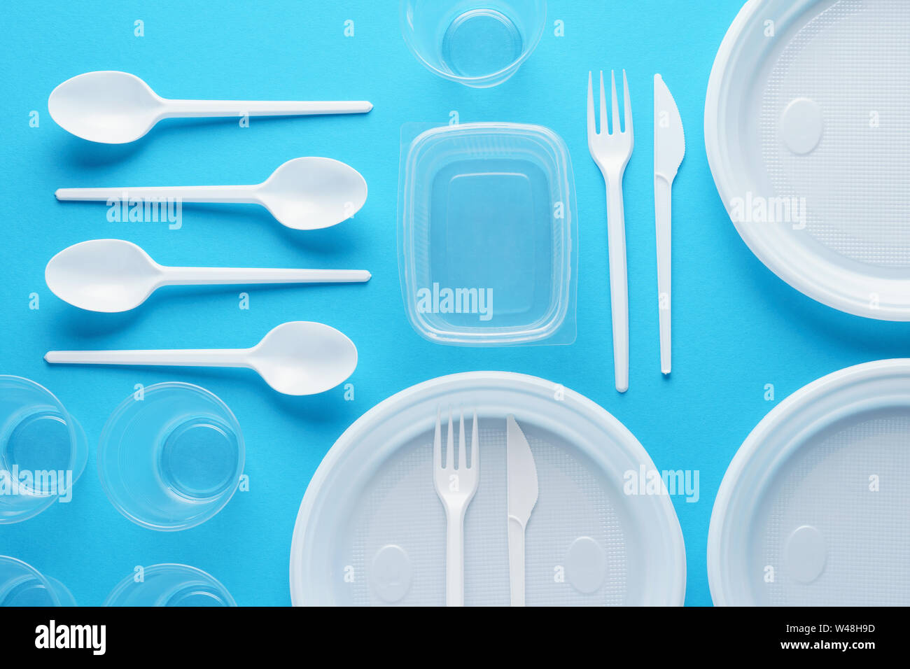Various white plastic disposable tableware on blue background. Creative ...