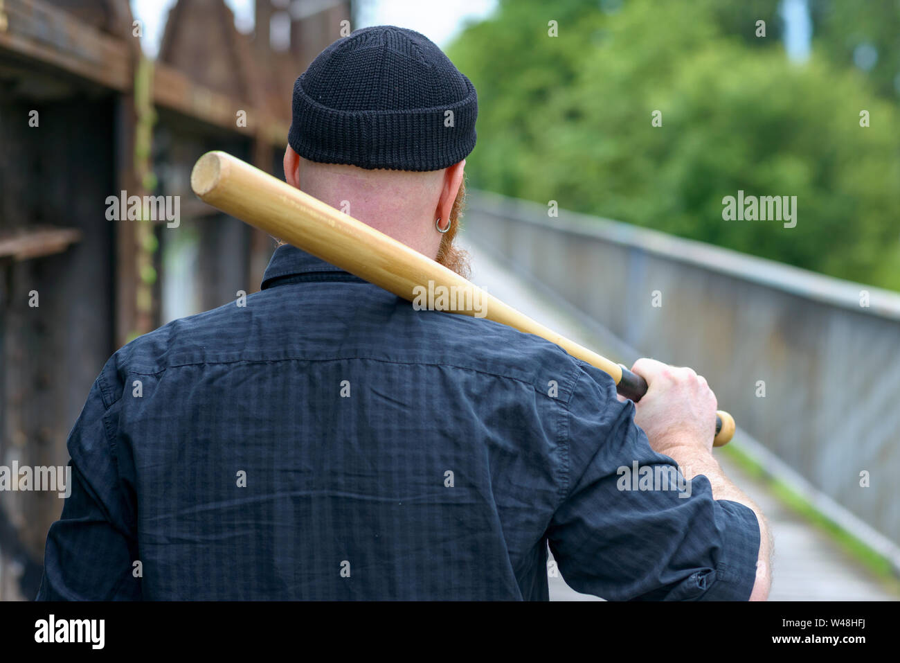 Man wearing a gold earring and beanie hat crossing a bridge with a ...