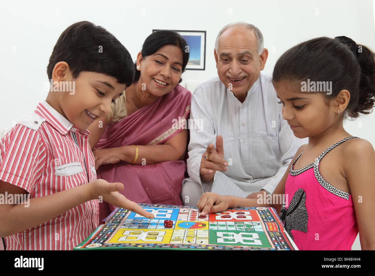 Boy and girl playing Ludo with their grandparents Stock Photo - Alamy