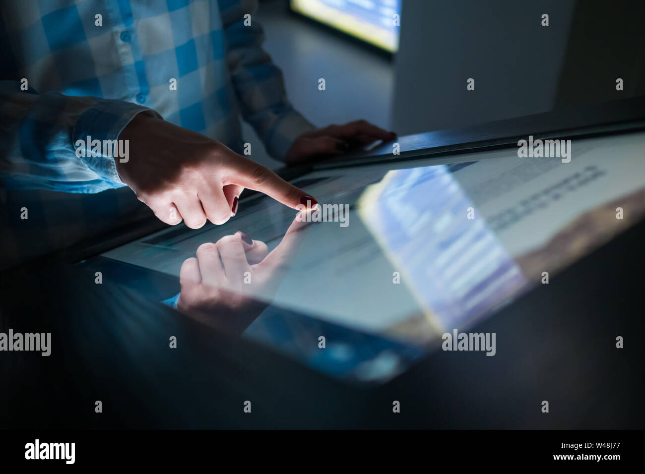 Woman hand using multimedia touchscreen display of interactive kiosk ...