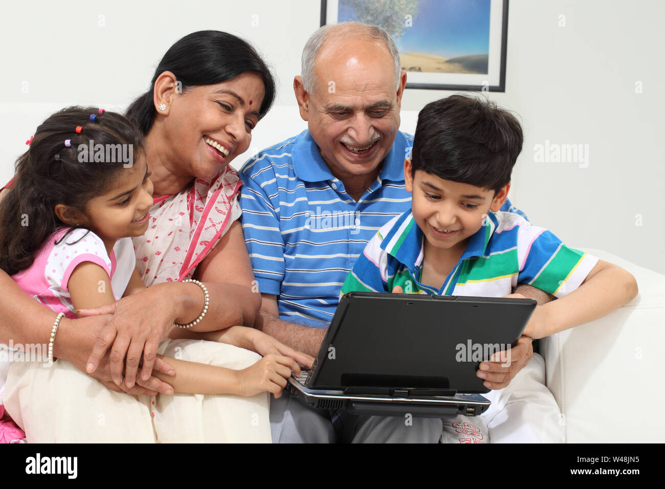 Family using laptop and smiling Stock Photo - Alamy
