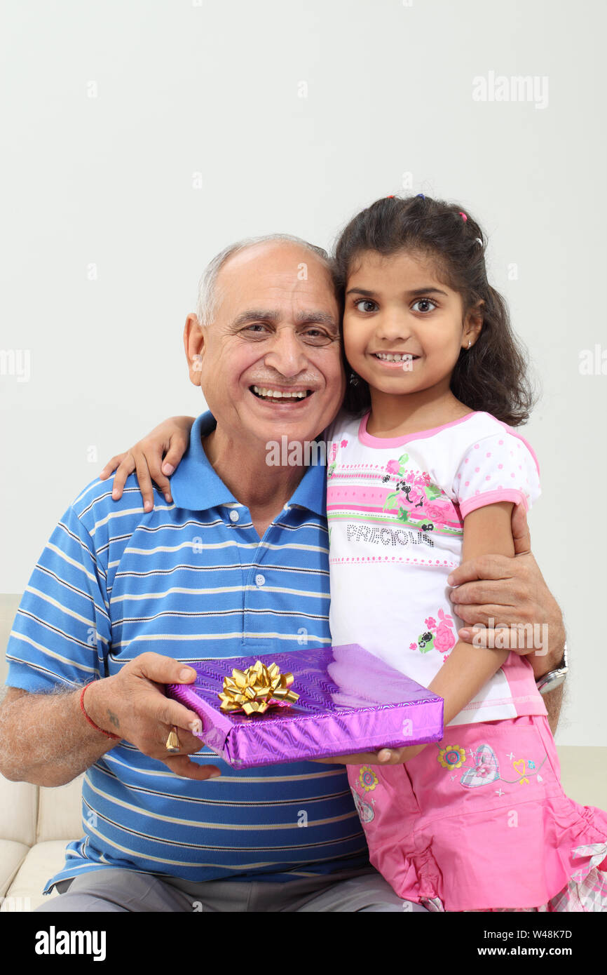 Girl receiving gift from her grandfather Stock Photo - Alamy