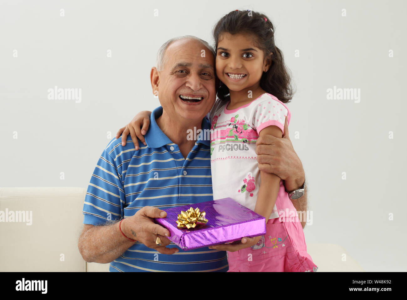 Girl receiving gift from her grandfather Stock Photo - Alamy
