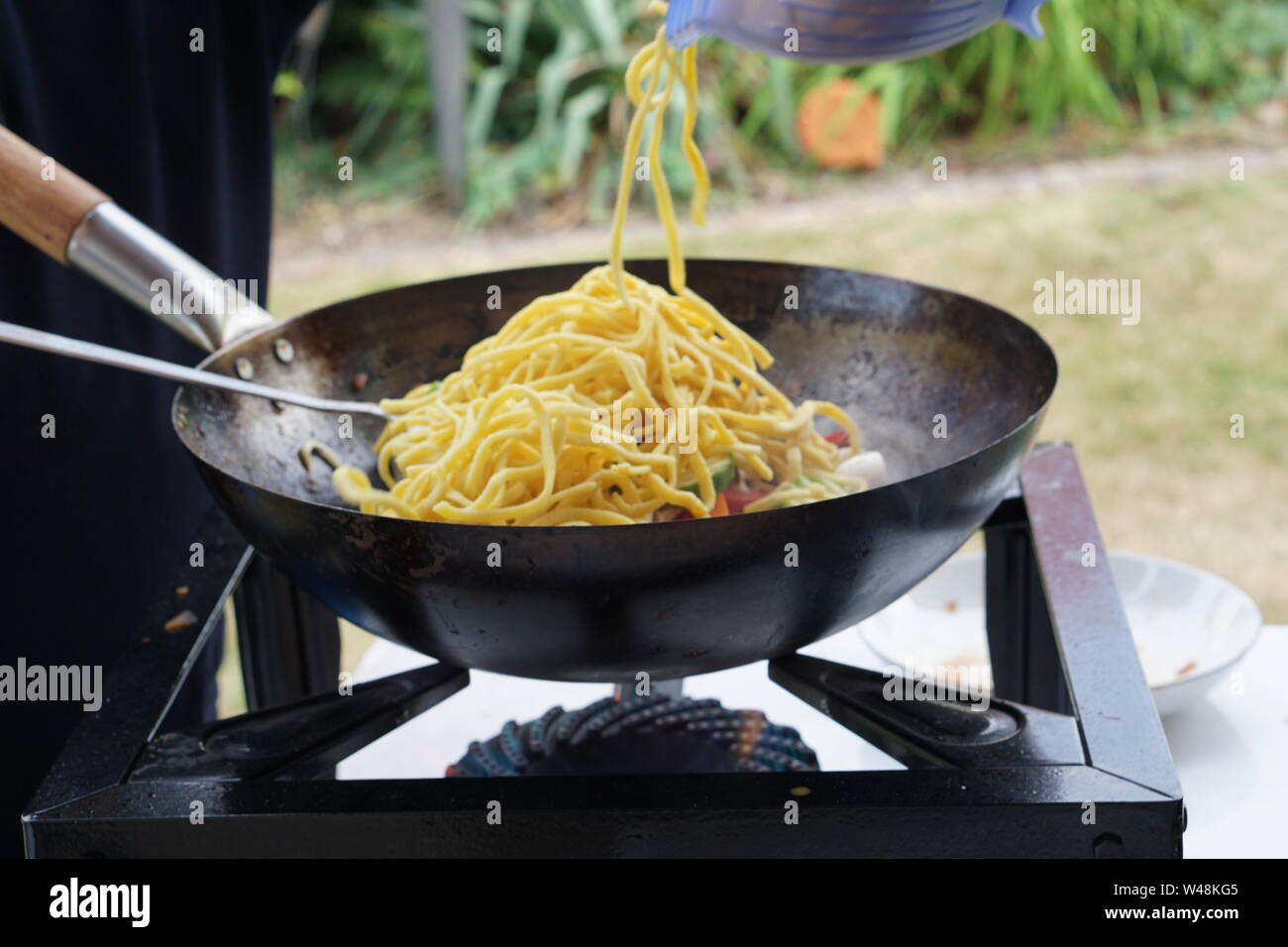 Cooking asian food in a wok pan Stock Photo - Alamy