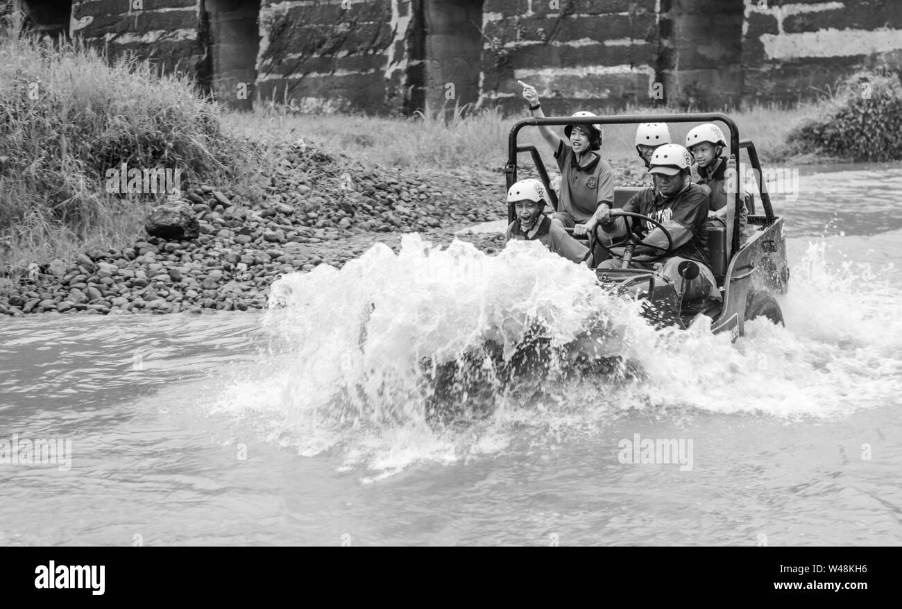 An Indonesian family ride an doorless jeep into a water body during an ...