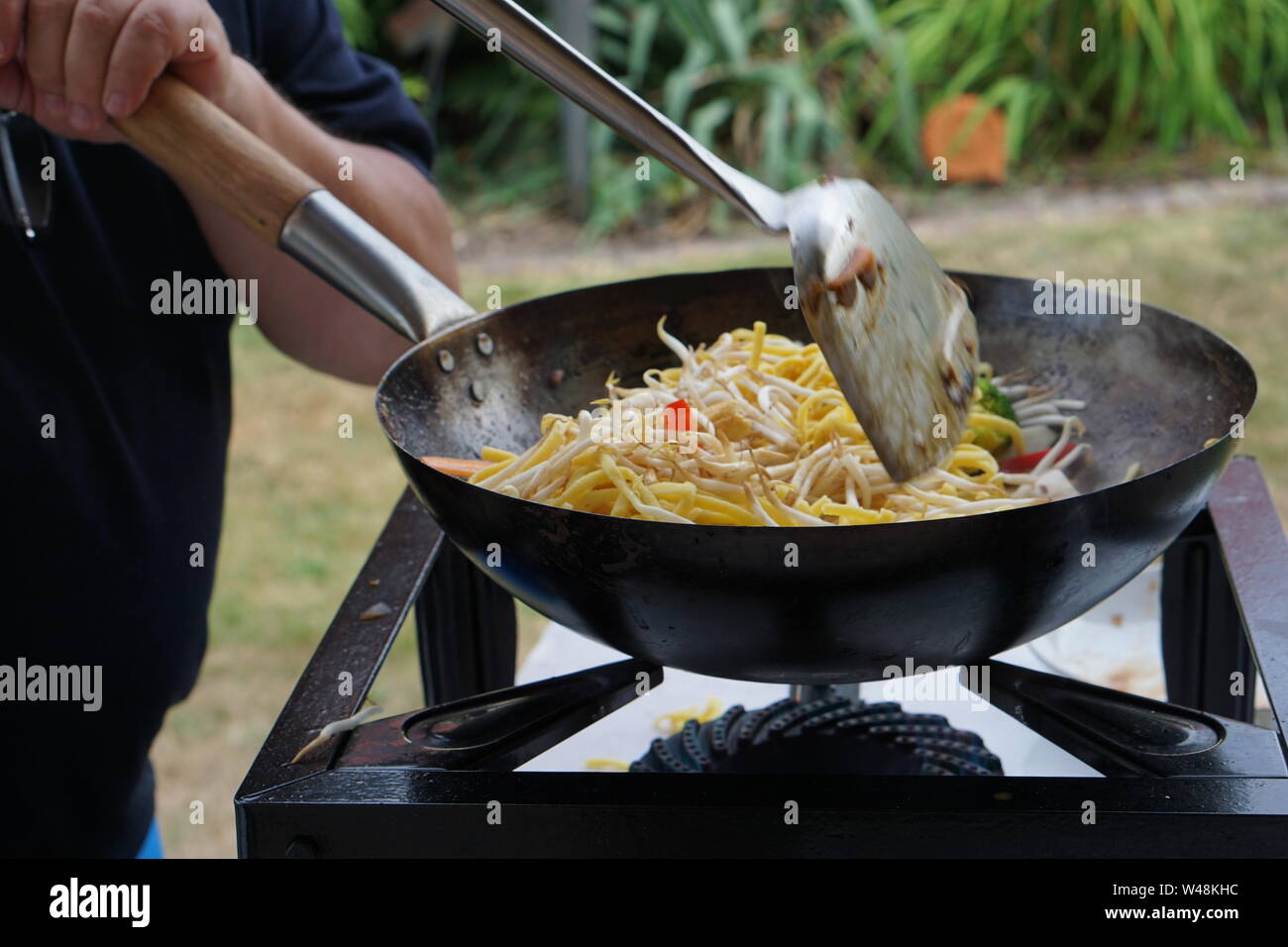 Cooking asian food in a wok pan Stock Photo - Alamy