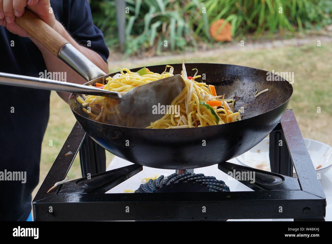 Cooking asian food in a wok pan Stock Photo - Alamy