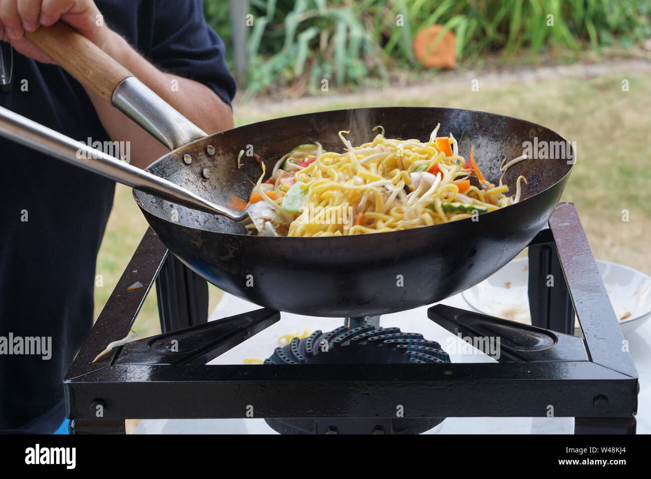 Cooking asian food in a wok pan Stock Photo - Alamy