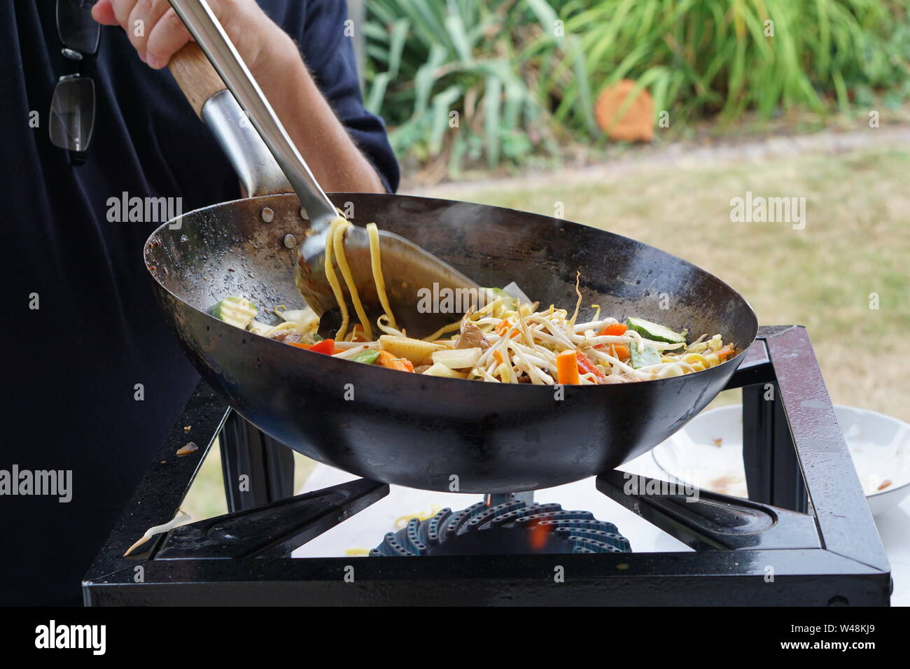 Cooking asian food in a wok pan Stock Photo - Alamy