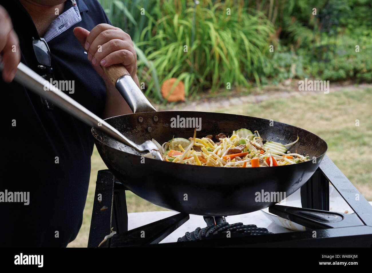 Cooking asian food in a wok pan Stock Photo - Alamy