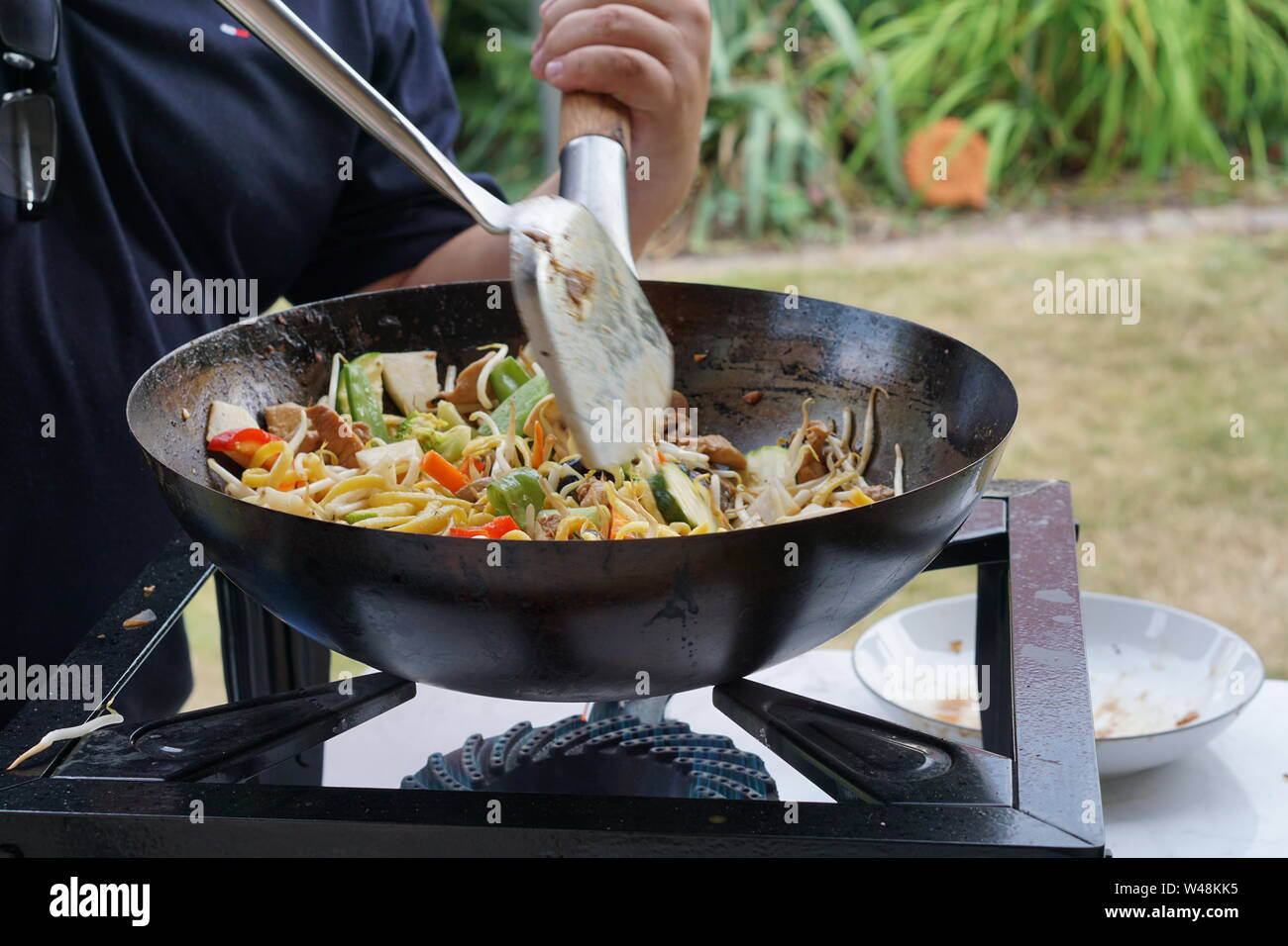 Cooking asian food in a wok pan Stock Photo - Alamy