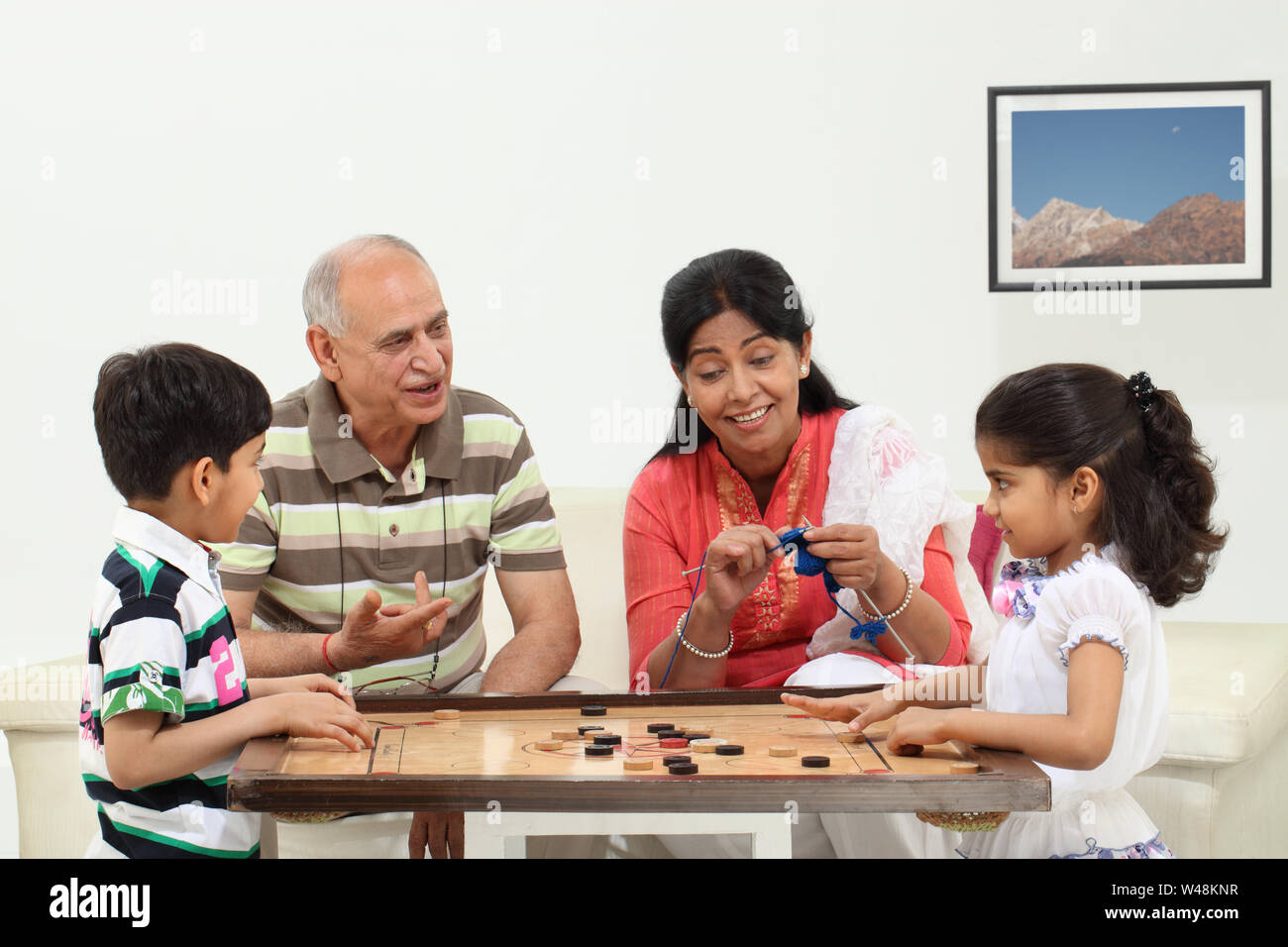 Boy and girl playing Carom with their grandparents Stock Photo - Alamy