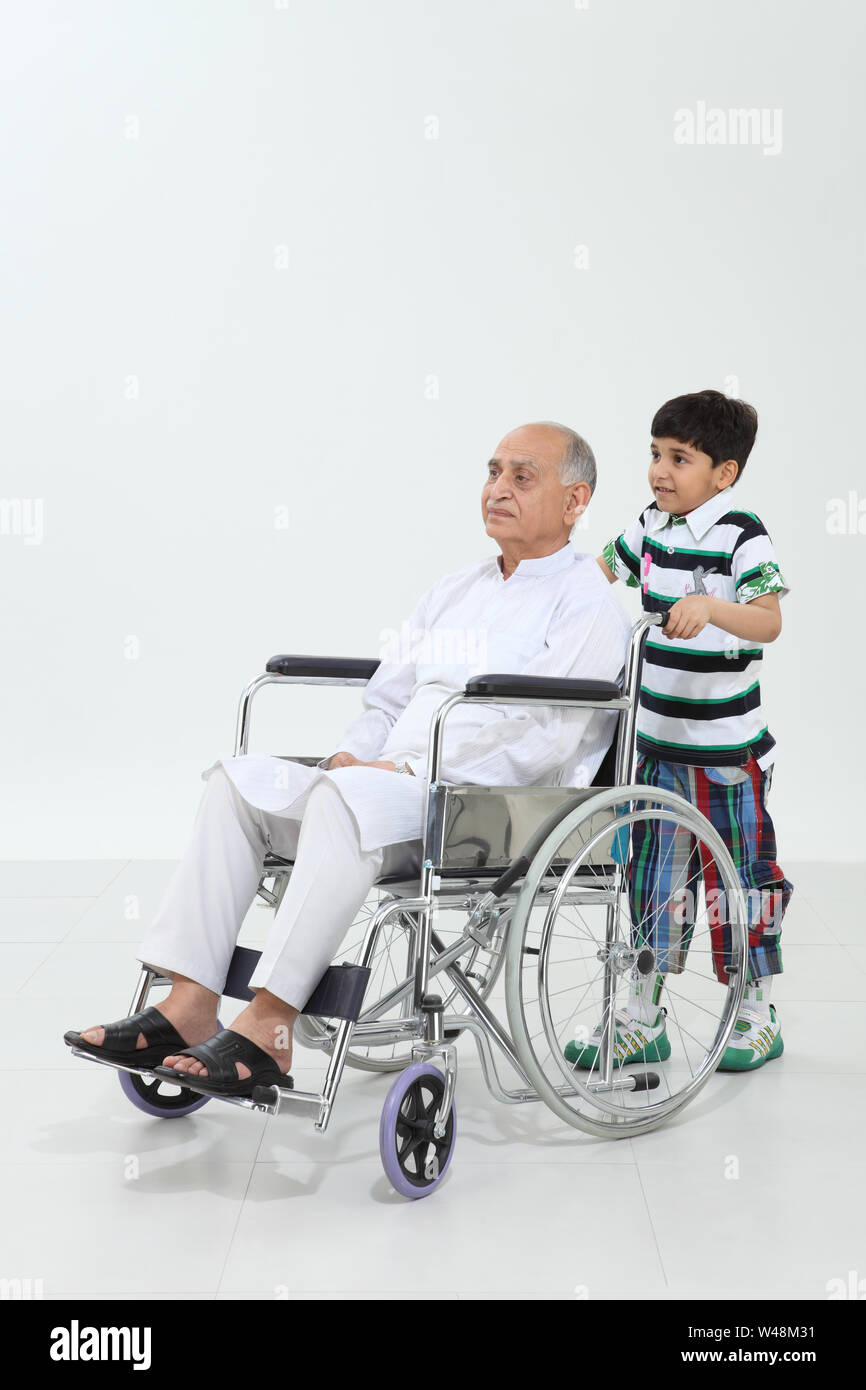 Boy pushing her grandfather on a wheelchair Stock Photo - Alamy