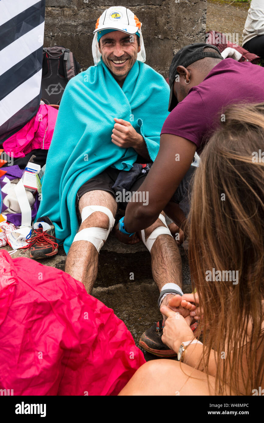 Running repairs! An injured runner puts on a brave face as he receives ...