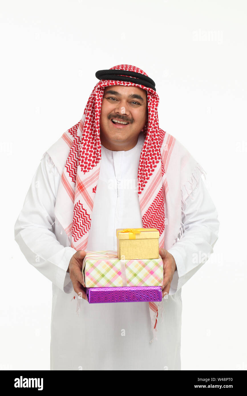 Arabian man holding stack of gifts and smiling Stock Photo - Alamy