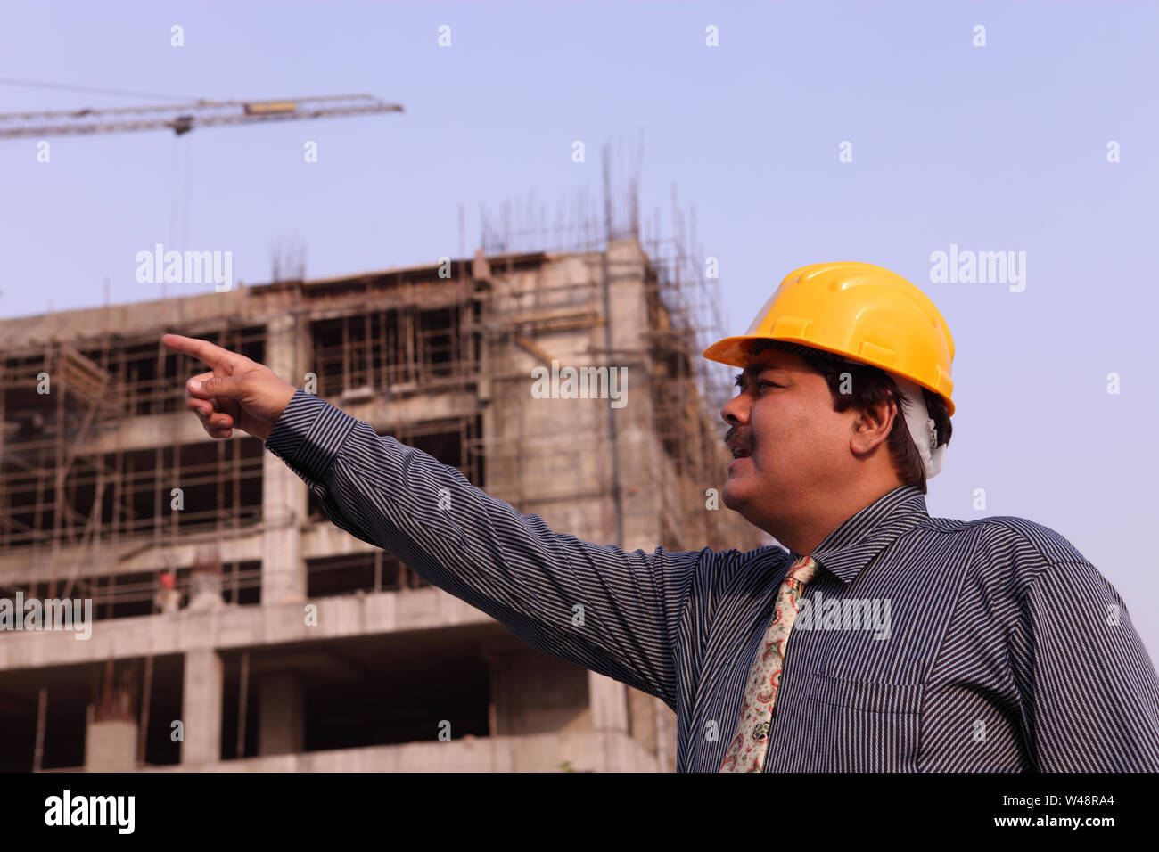 Indian architect pointing at construction site Stock Photo - Alamy