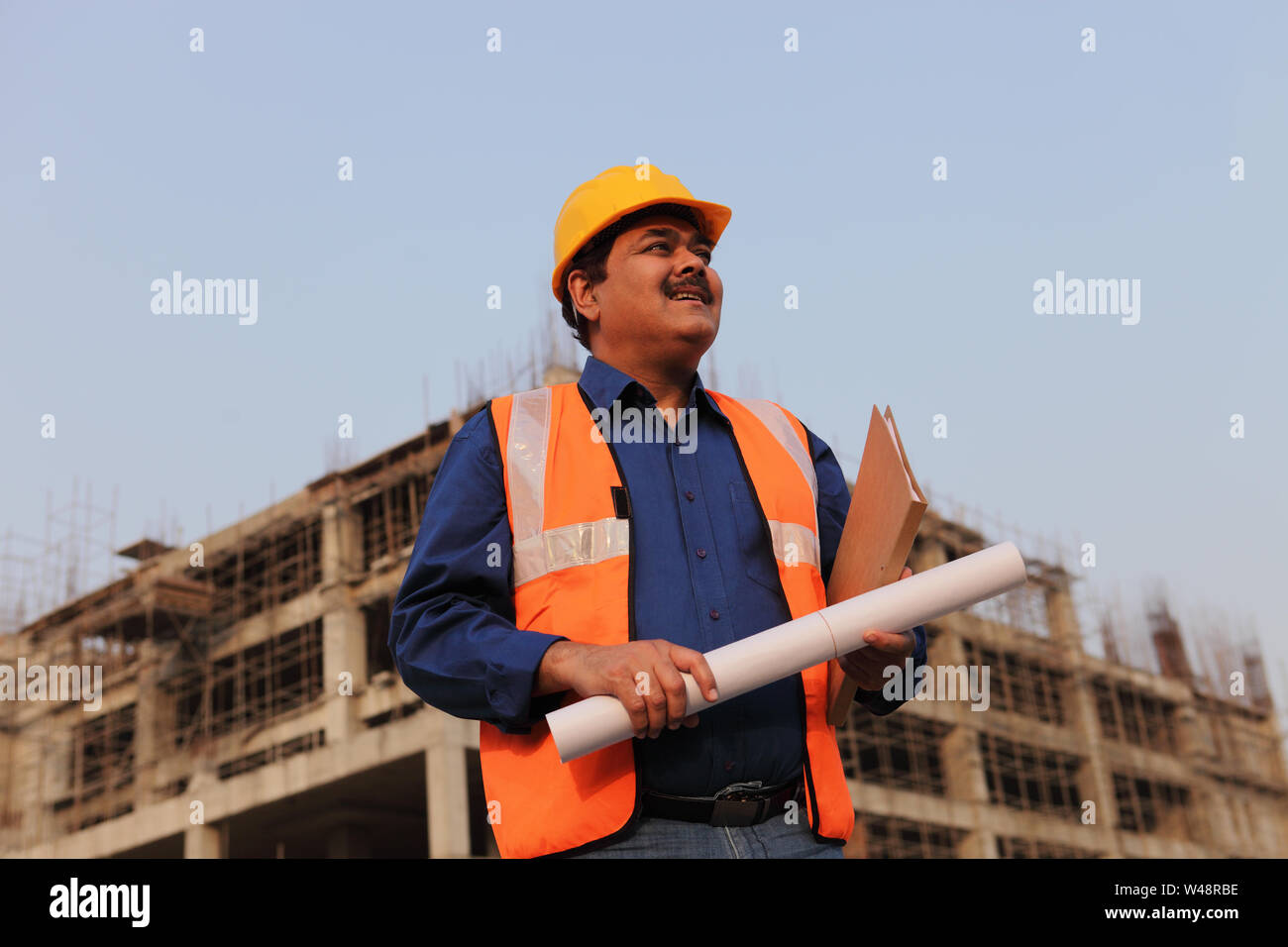 Architect holding blueprint at construction site Stock Photo - Alamy
