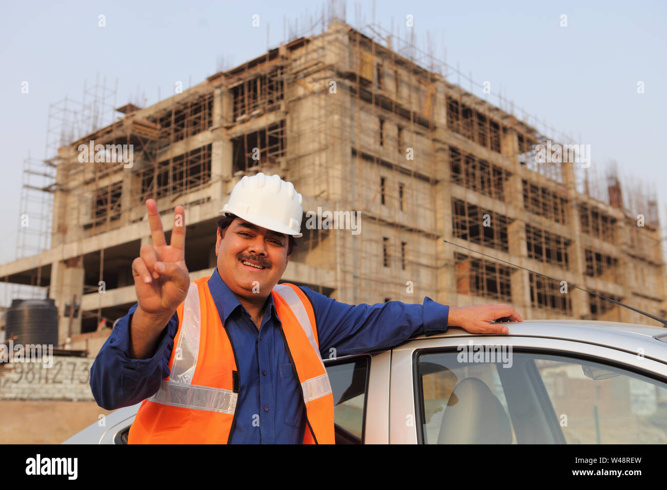 Architect showing V sign at construction site Stock Photo - Alamy