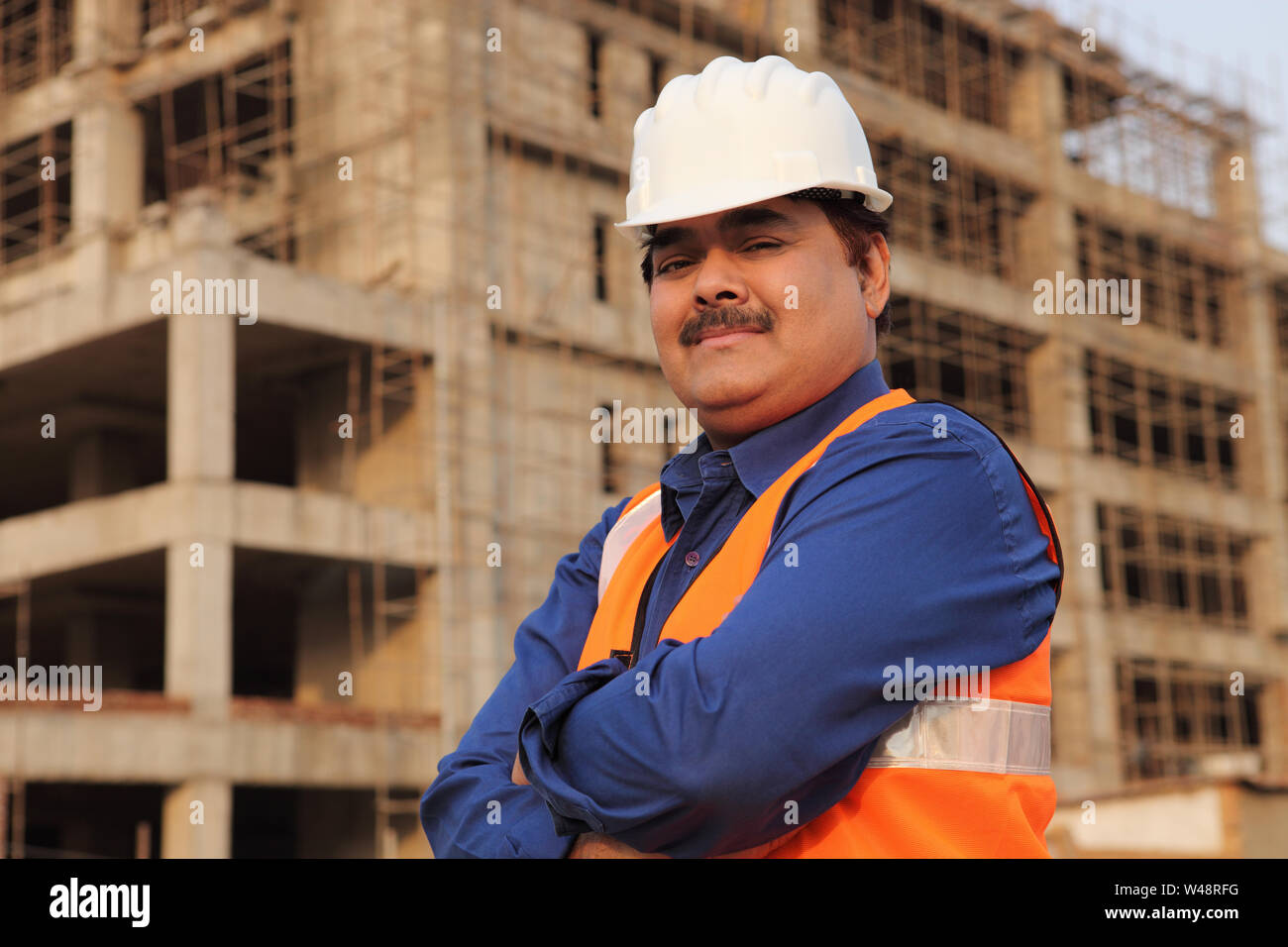 Portrait of an architect with his arms crossed at construction site ...
